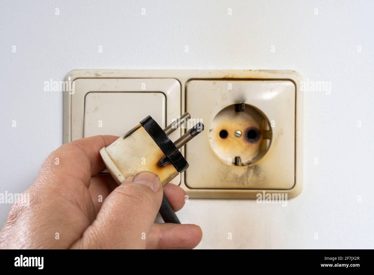 Hand Removing Plug From An Over Heated Socket Stock Photo - Alamy