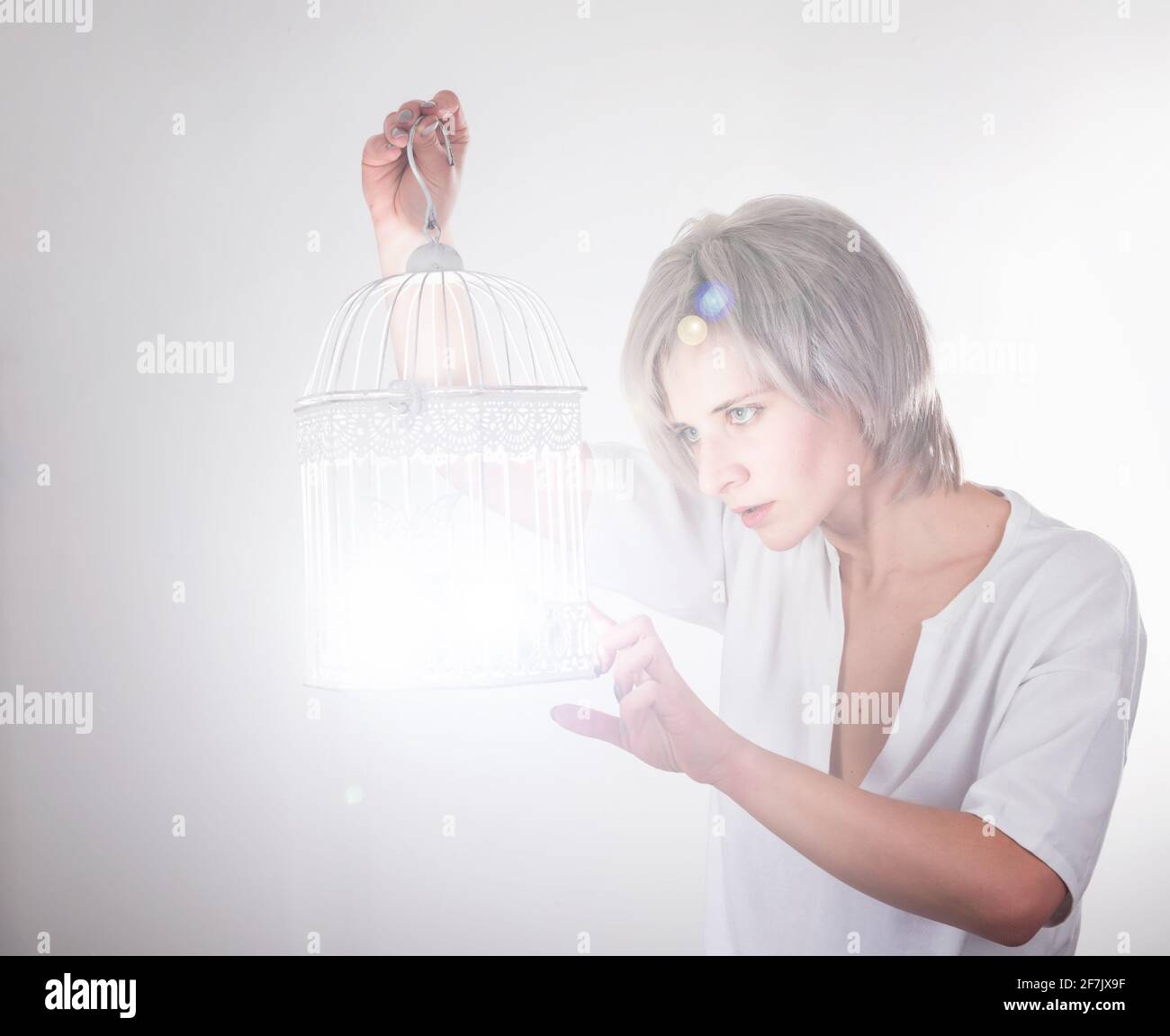 young blond woman catches a light to a bird cage Stock Photo - Alamy