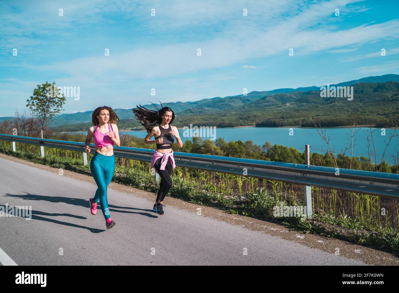 Sports young girls jogging near scenic lake. Active lifestyle girls ...