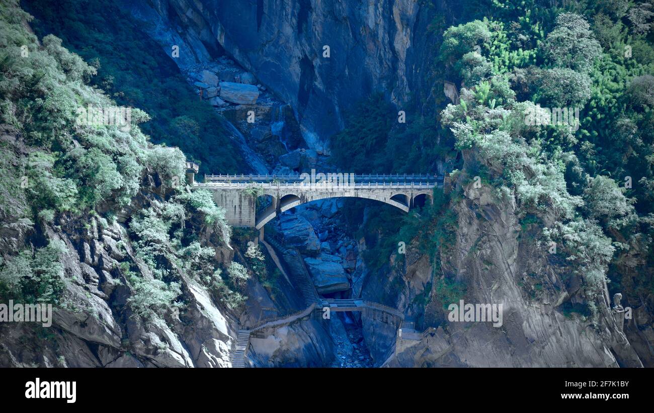 An old stone bridge at foot of mountain with green trees in Tiger ...