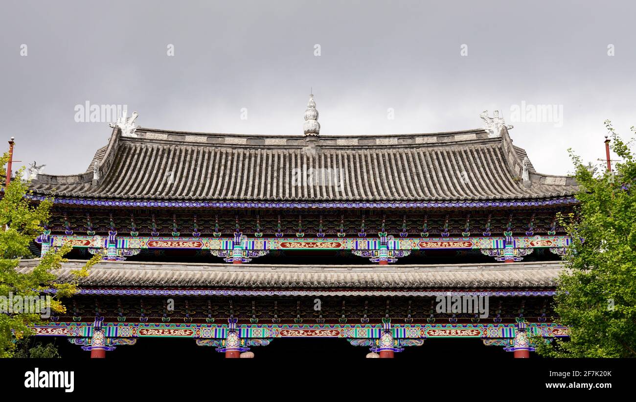 An ancient Chinese style palace with tile roof and trees on both sides ...