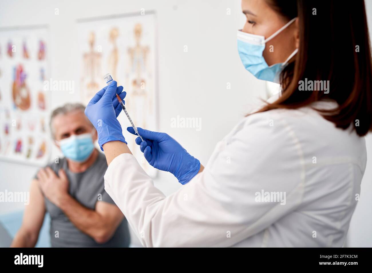 Female doctor preparing syringe for senior patient Stock Photo - Alamy