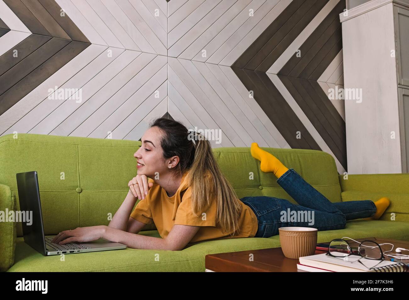 Young woman lying on the couch with her laptop Stock Photo - Alamy