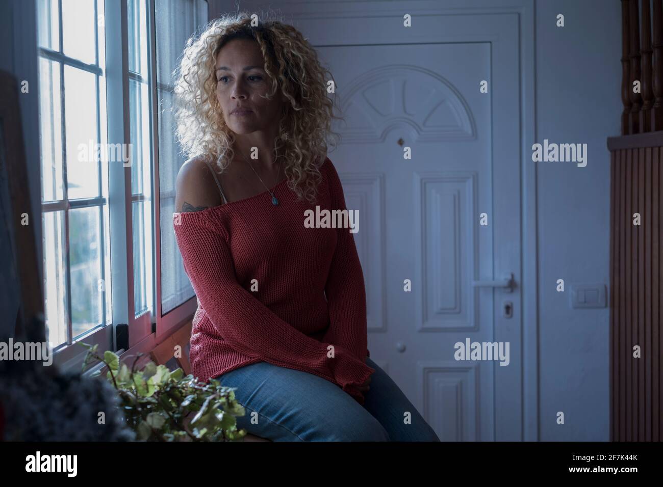 Sad woman alone at home looking outside the window - portrait of adult ...