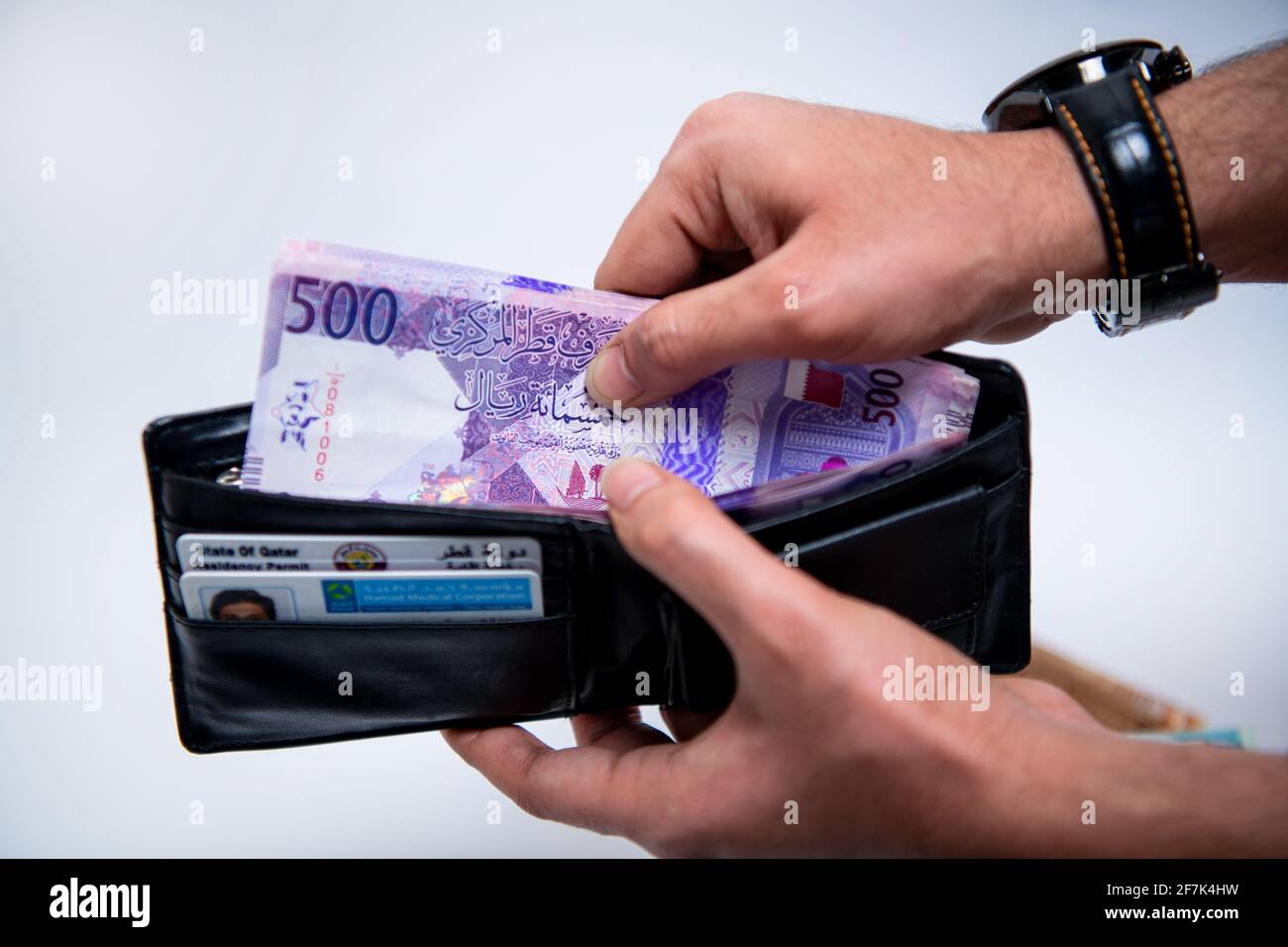 Men's hands holding wallet with Qatari notes. 500 Rial new notes ...
