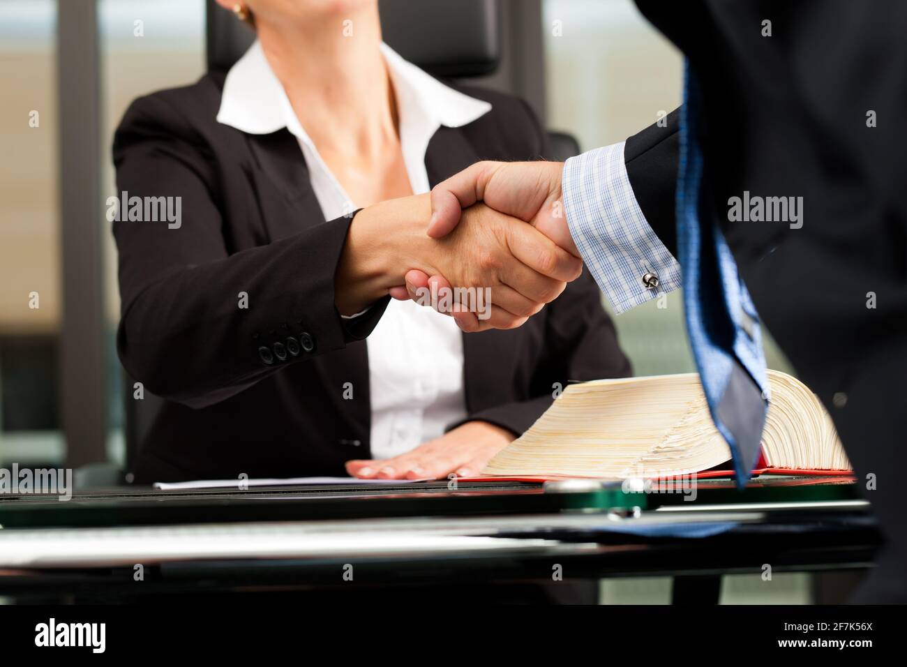 Mature female lawyer or notary with client in her office - handshake ...