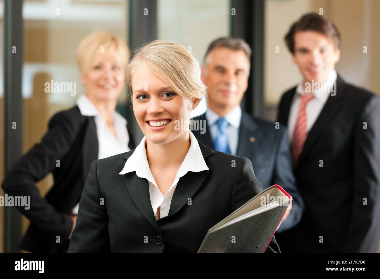 Business - team in an office; the junior manager is standing in front ...