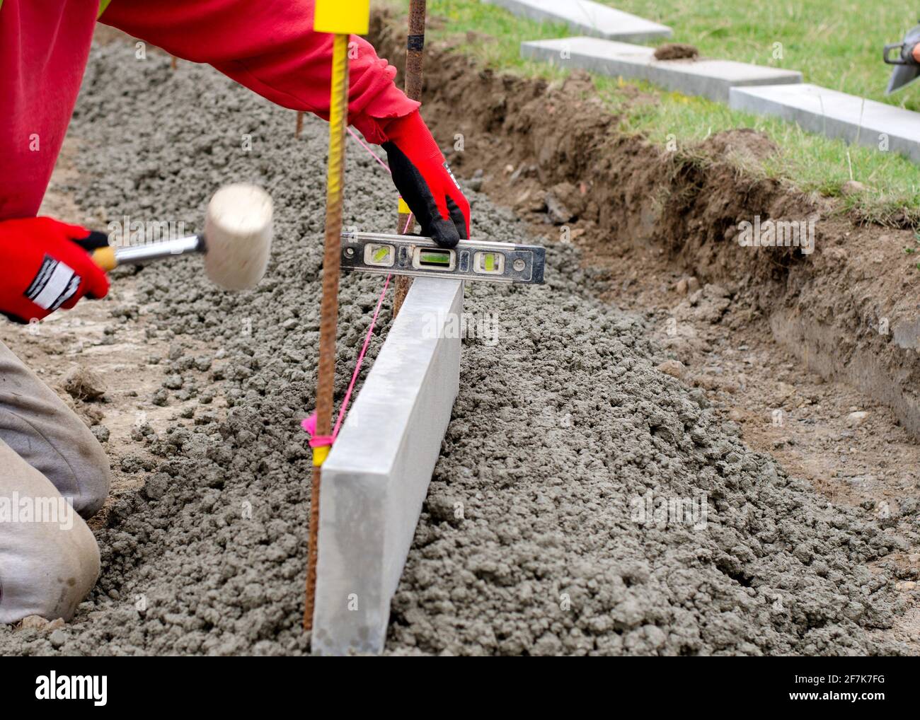 Laing edging kerb on semidry concrete during roadworks and new footpath ...