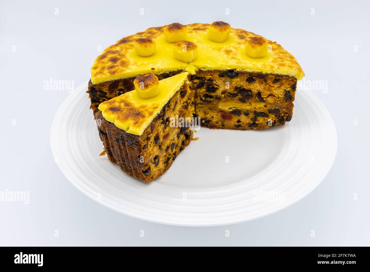Traditional home baked simnel cake with a cut slice on a white plate ...