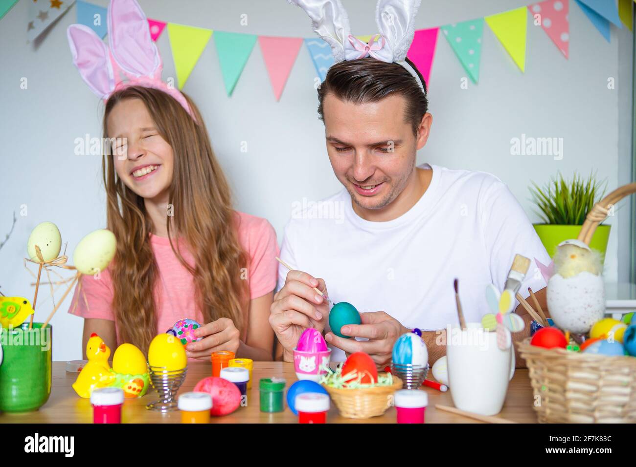 Father and his little daughter painting eggs. Happy family preparing ...
