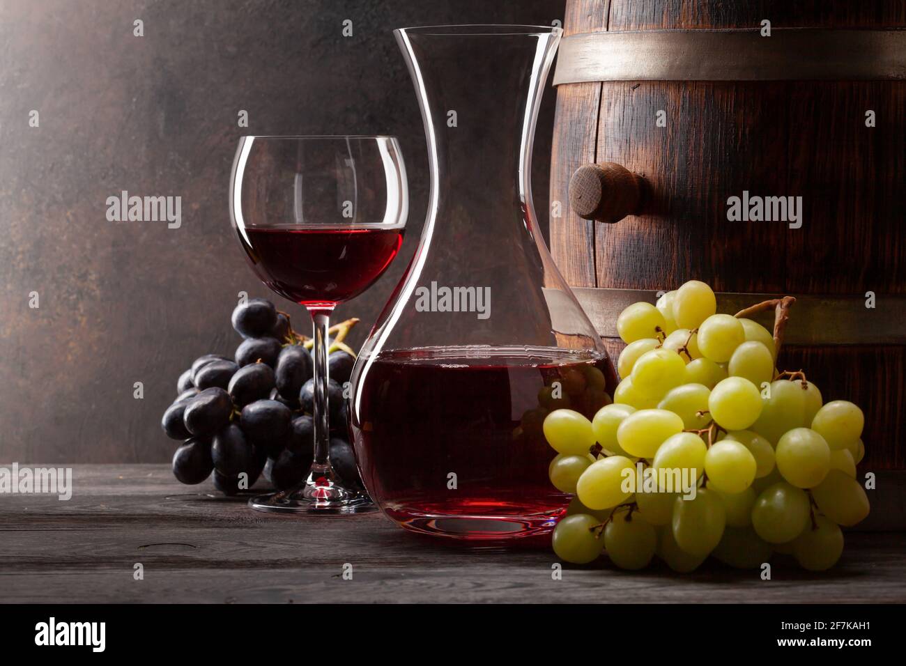 Wine decanter, glass of red wine and old wooden barrel. With copy space ...