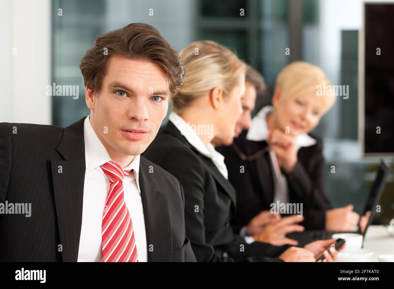Business - team in an office; a young colleague is looking into the ...