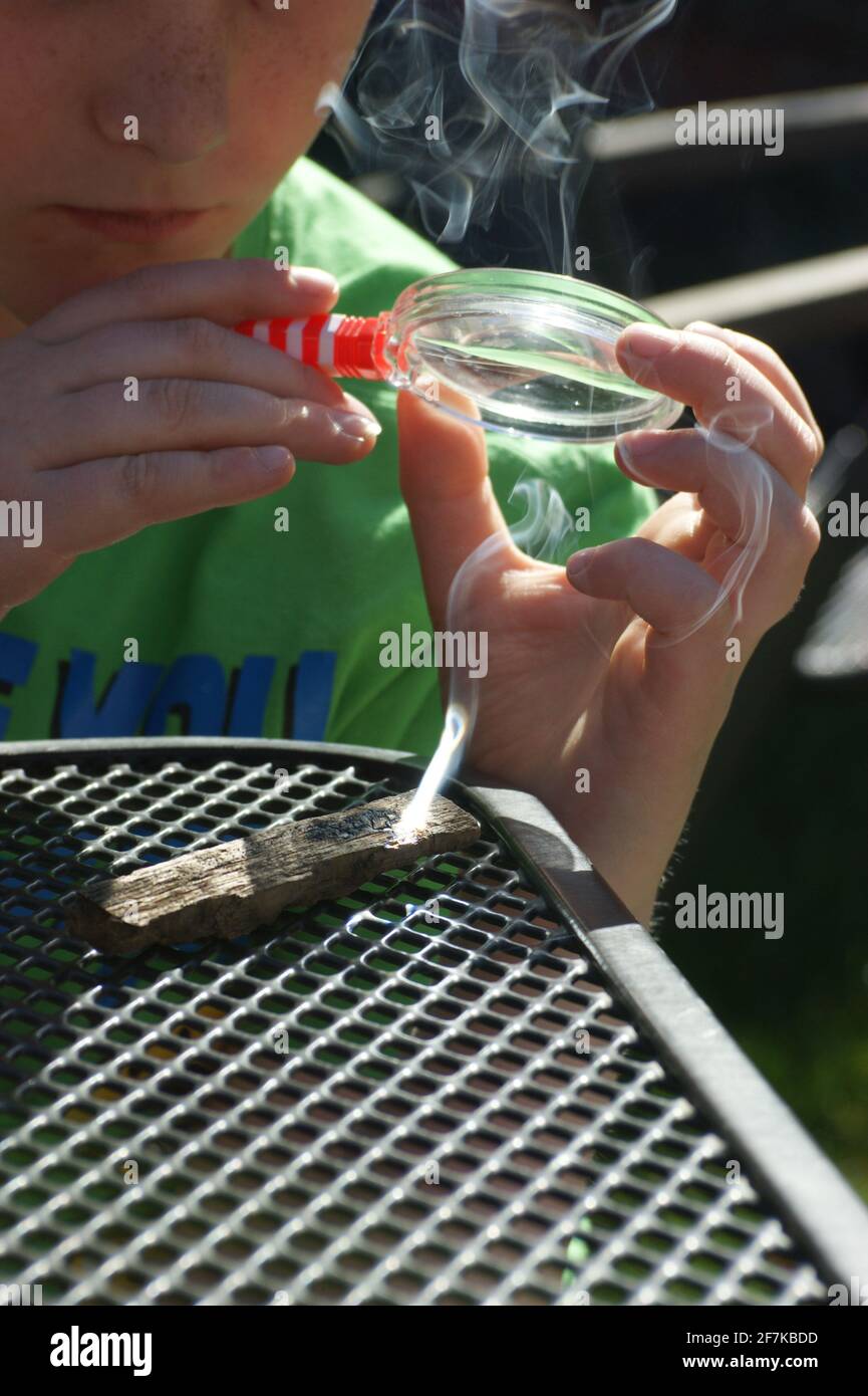 An Unrecognizable boy Starting a Fire with a Magnifying Glass outdoors ...
