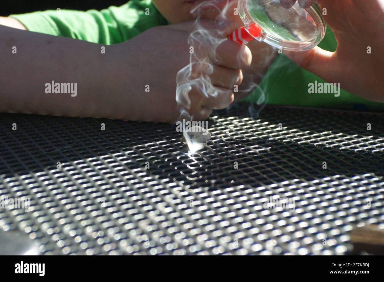 An Unrecognizable boy Starting a Fire with a Magnifying Glass outdoors ...