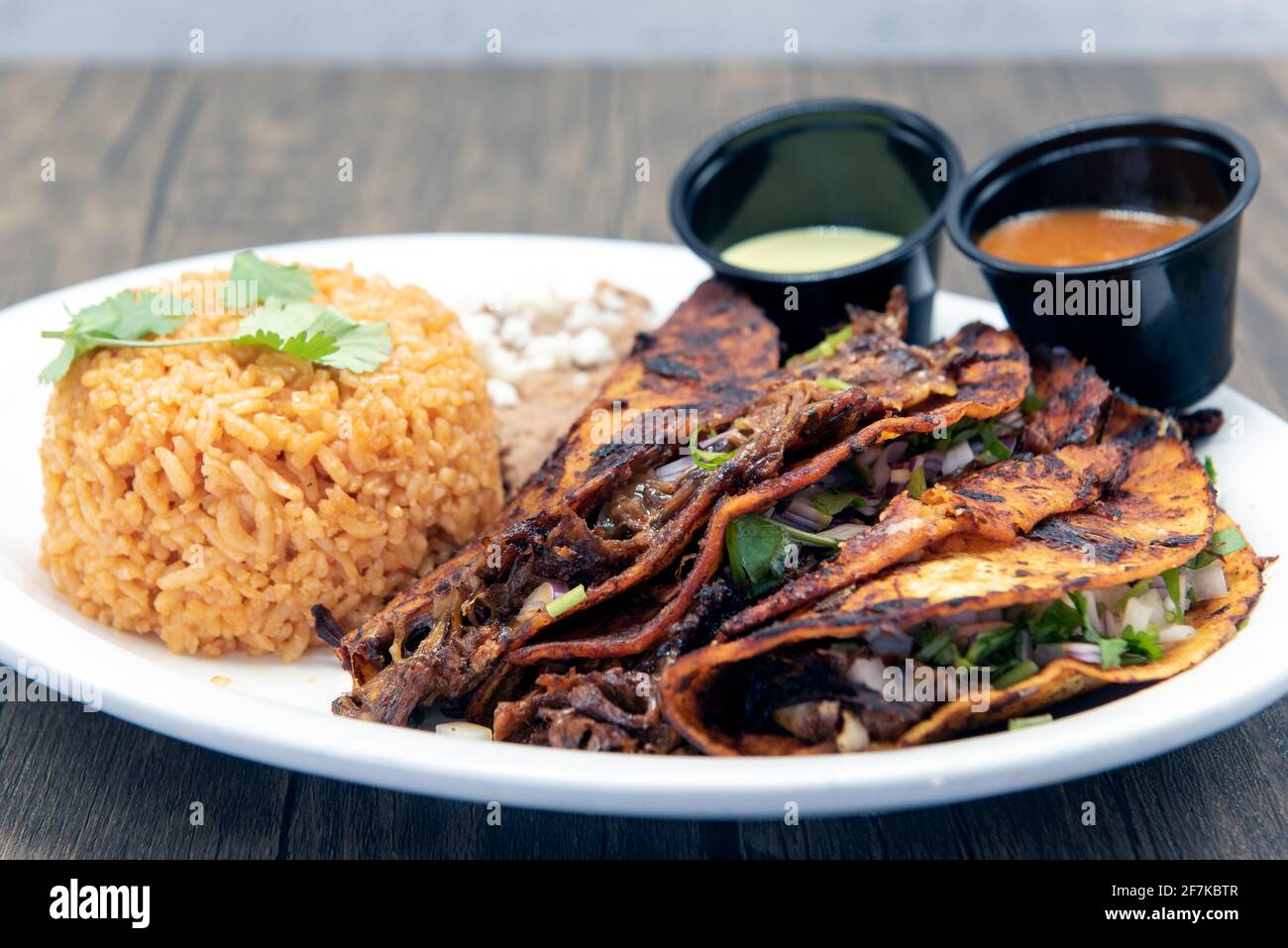 Threesome of red birria tacos fried to perfection served on a plate ...