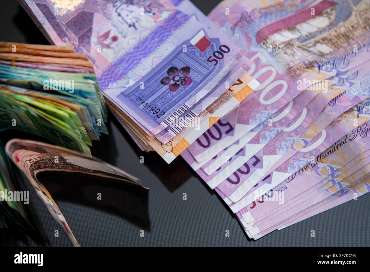 Men's hands holding and Counting Qatari Bank notes. 500 Rial new notes ...