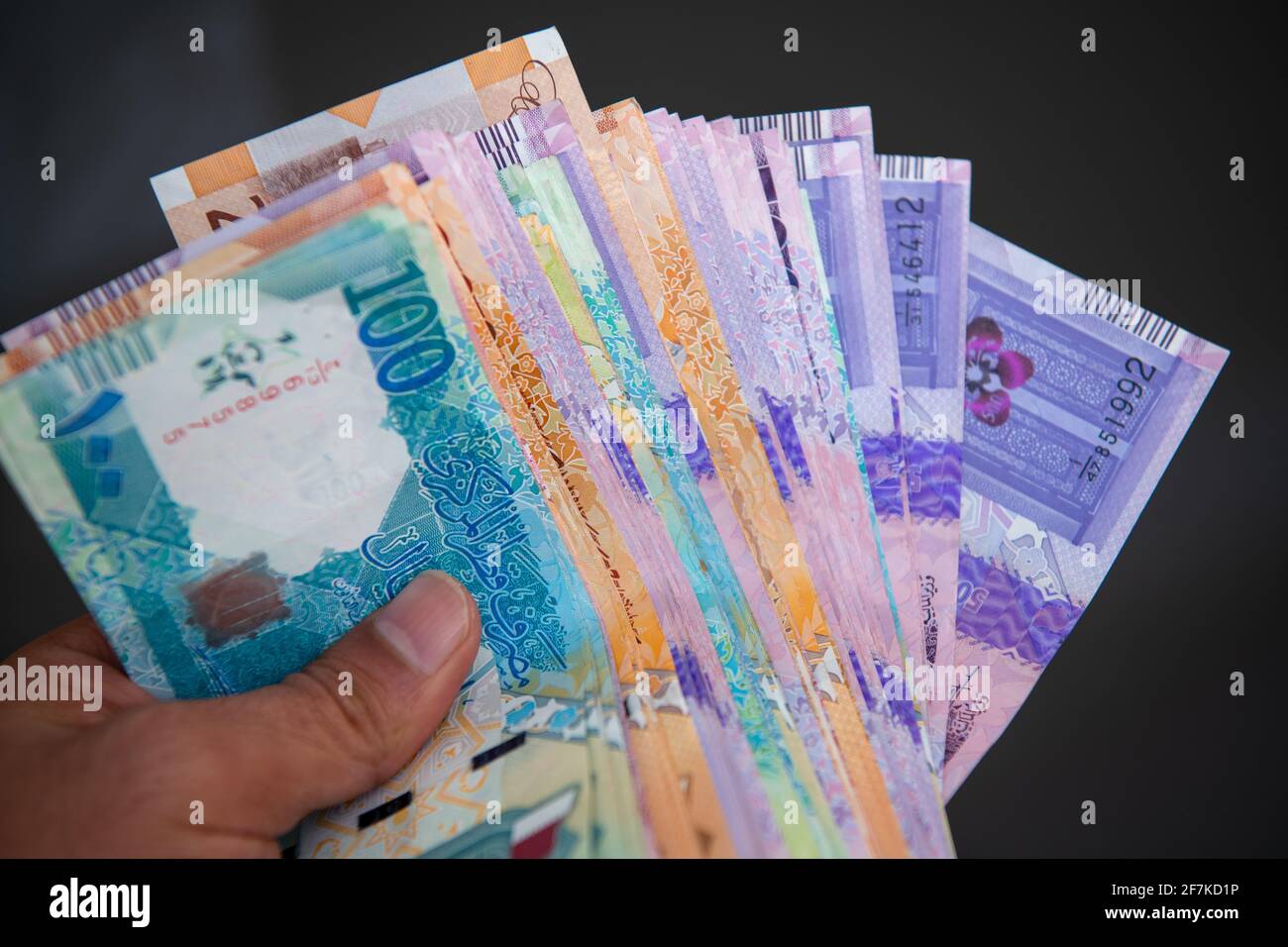 Men's hands holding and Counting Qatari Bank notes. 500 Rial new notes ...