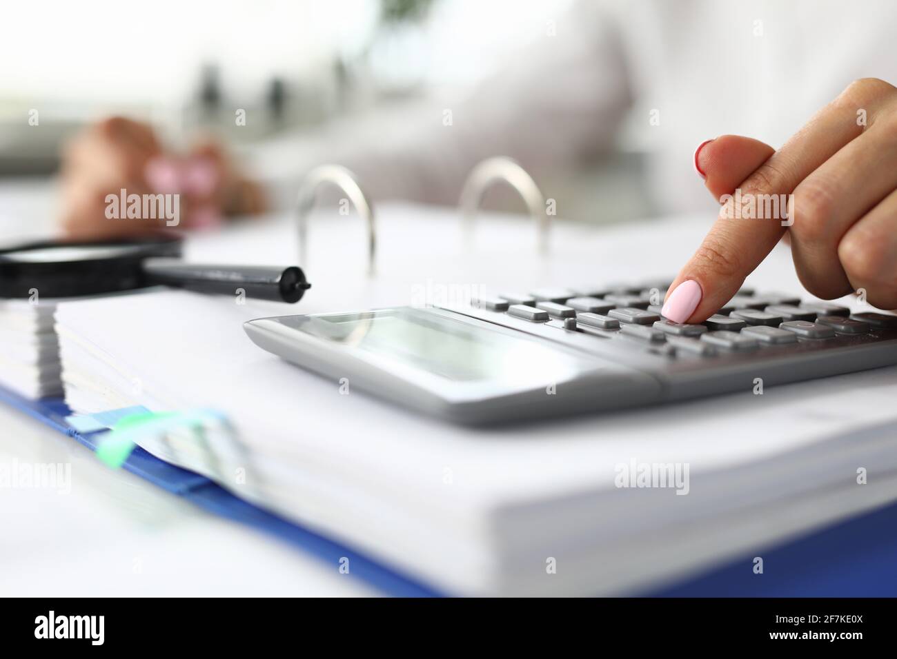 Woman counting on calculator at table with documents closeup ...