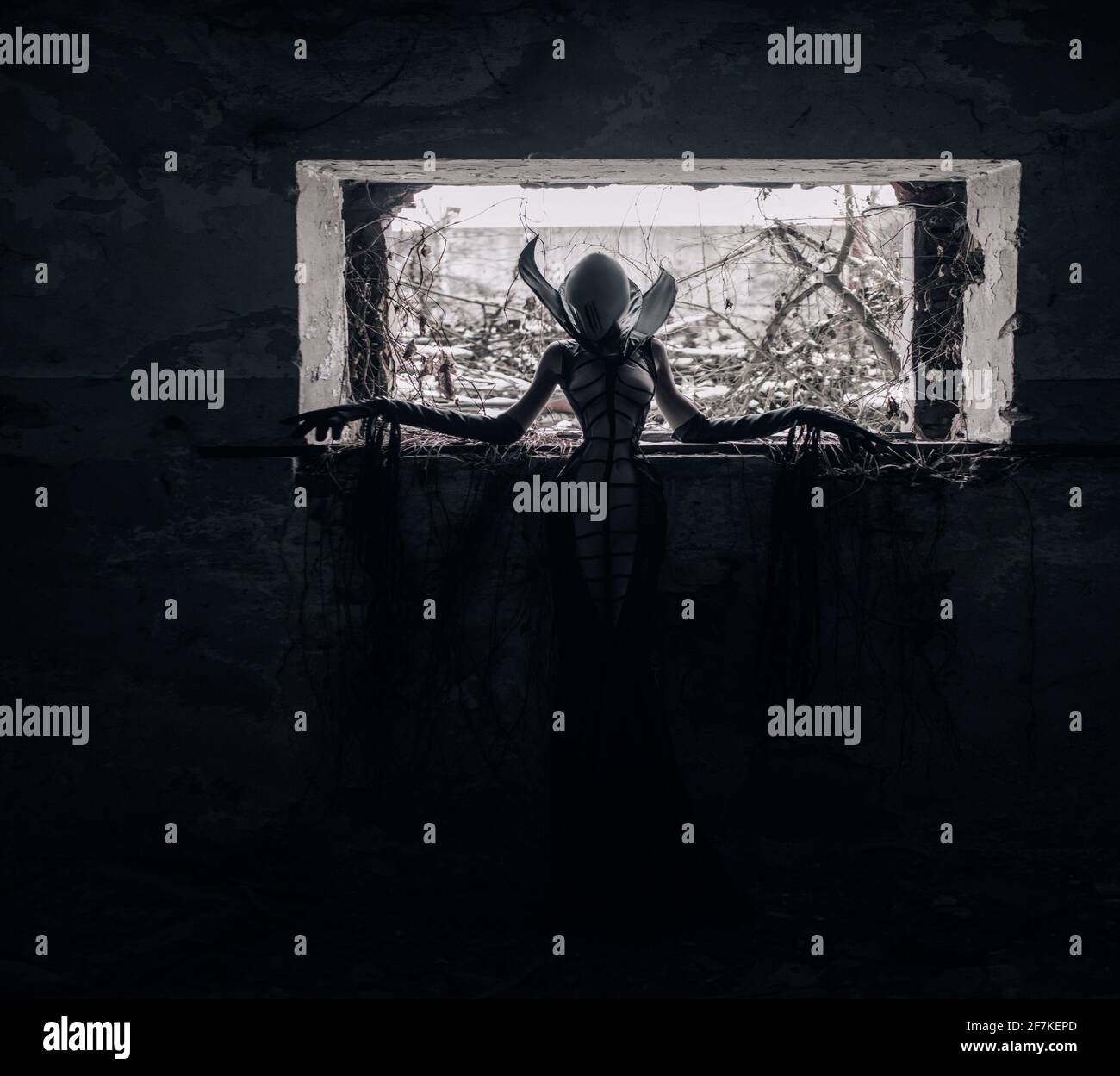 Woman in the image of the alien creature stands inside old abandoned ...