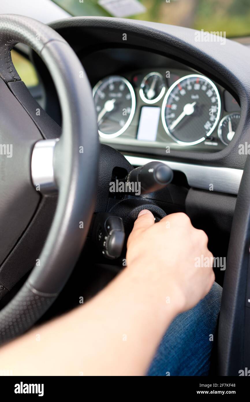 Man is starting his car; he is turning the ignition key under the wheel ...