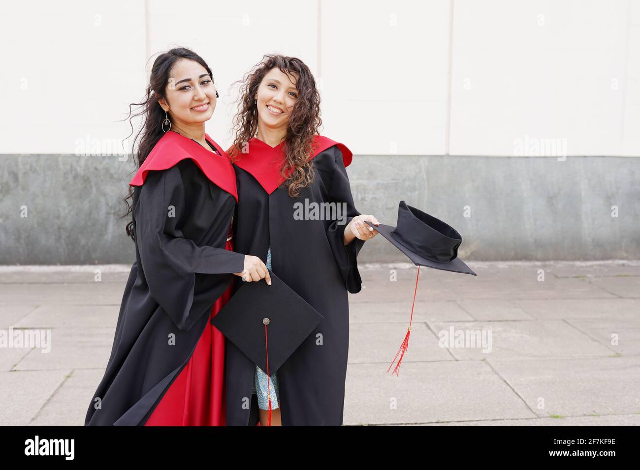 Portrait of successful graduate female students wearing cap outdoors ...
