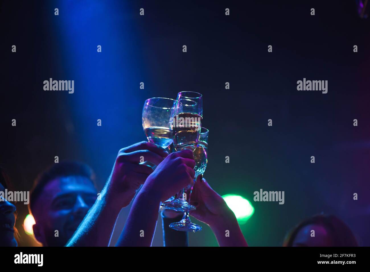Young friends dancing with glasses of champagne in hands. Against ...