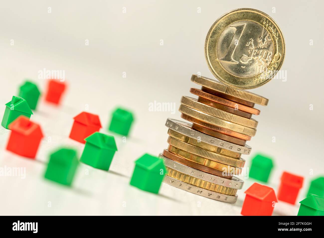 Coin stack with many house plastic models on wooden table. Saving ...