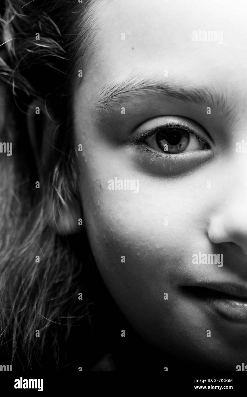 A close up portrait of a young girl, with only half the face visible ...