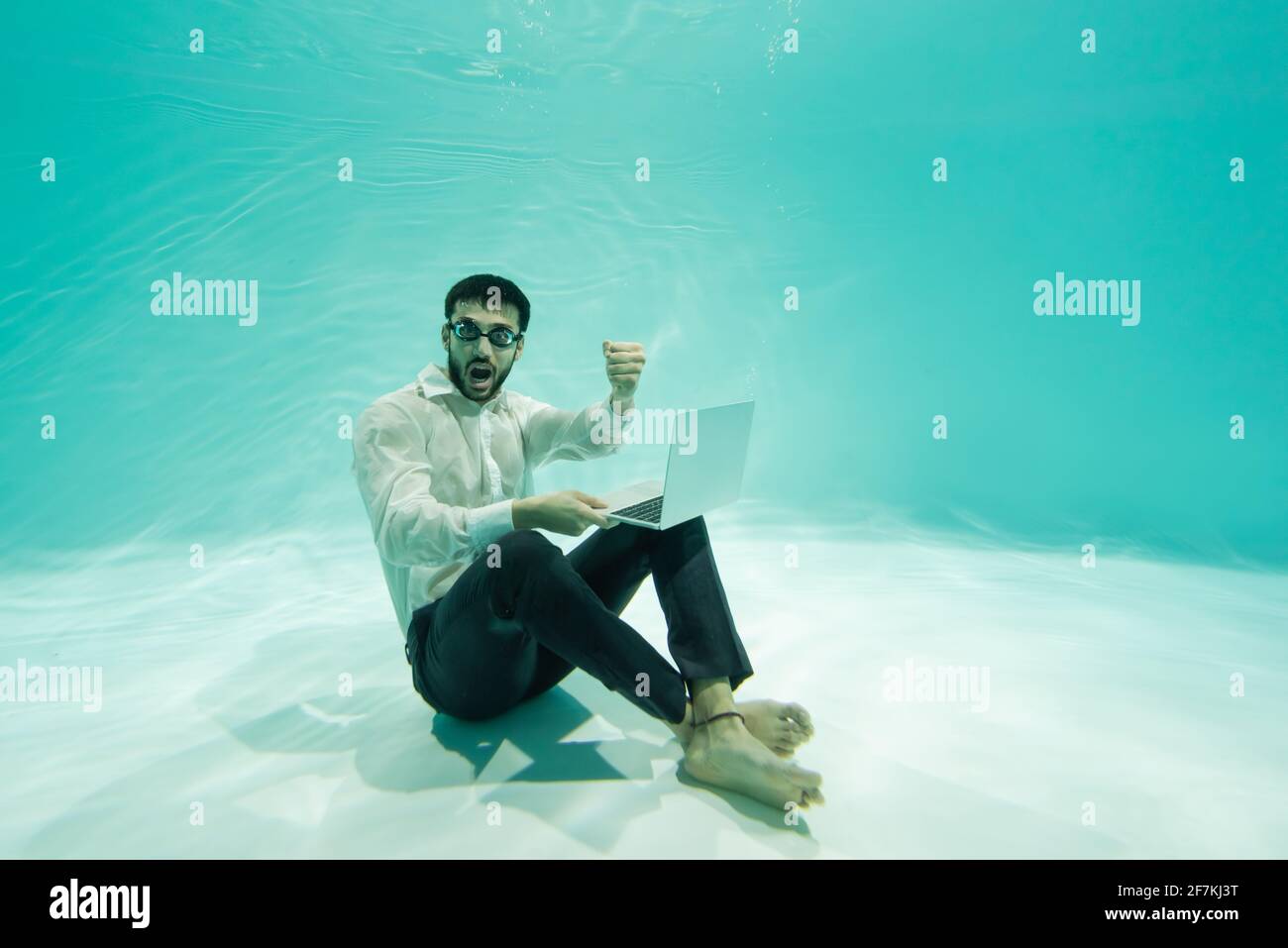 Excited muslim businessman showing yes gesture and holding laptop in ...