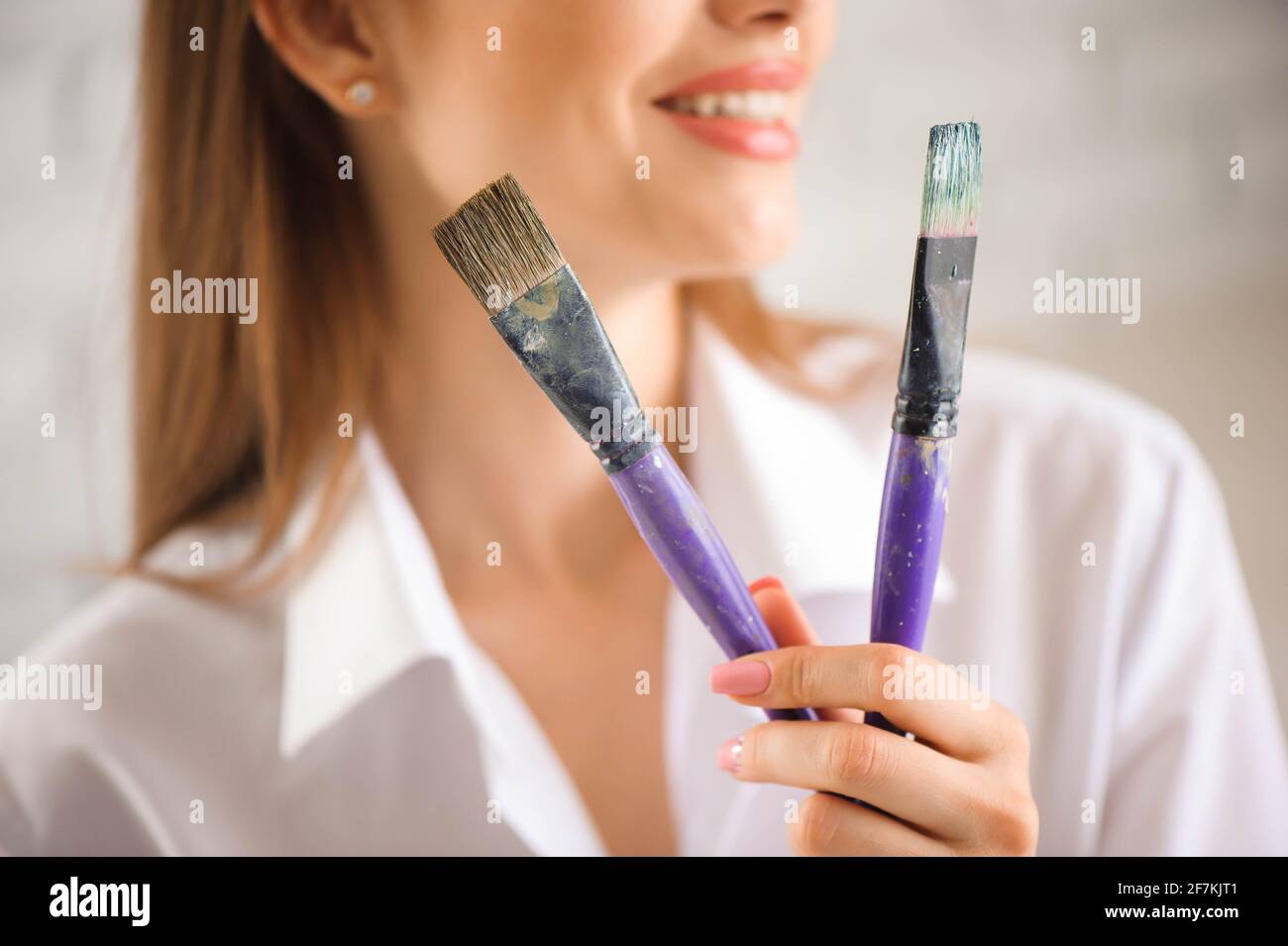 Portrait of talented young woman painting picture in art studio with ...