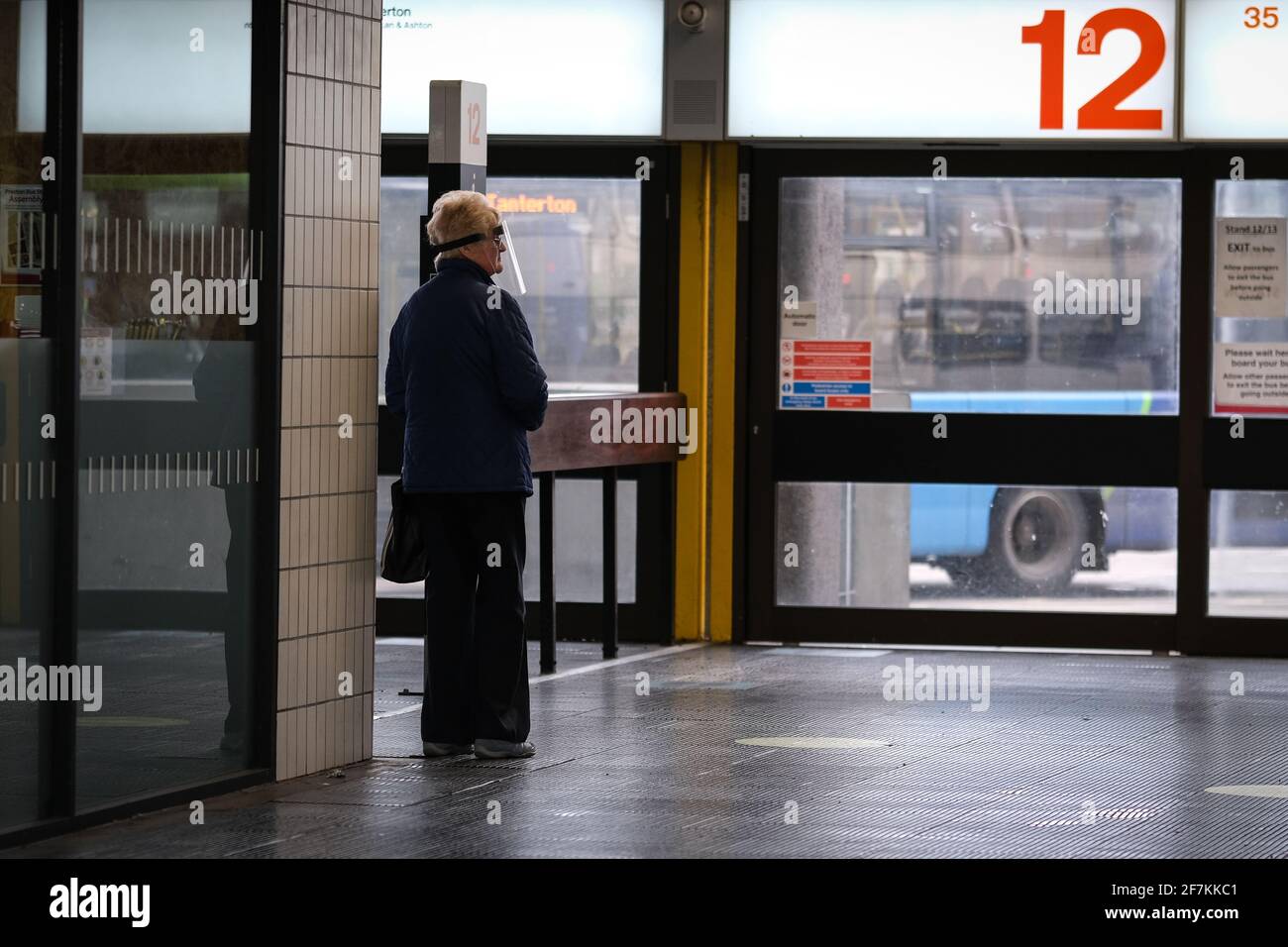 A woman in a perspex face mask waiting for a bus at Preston Bus Station ...