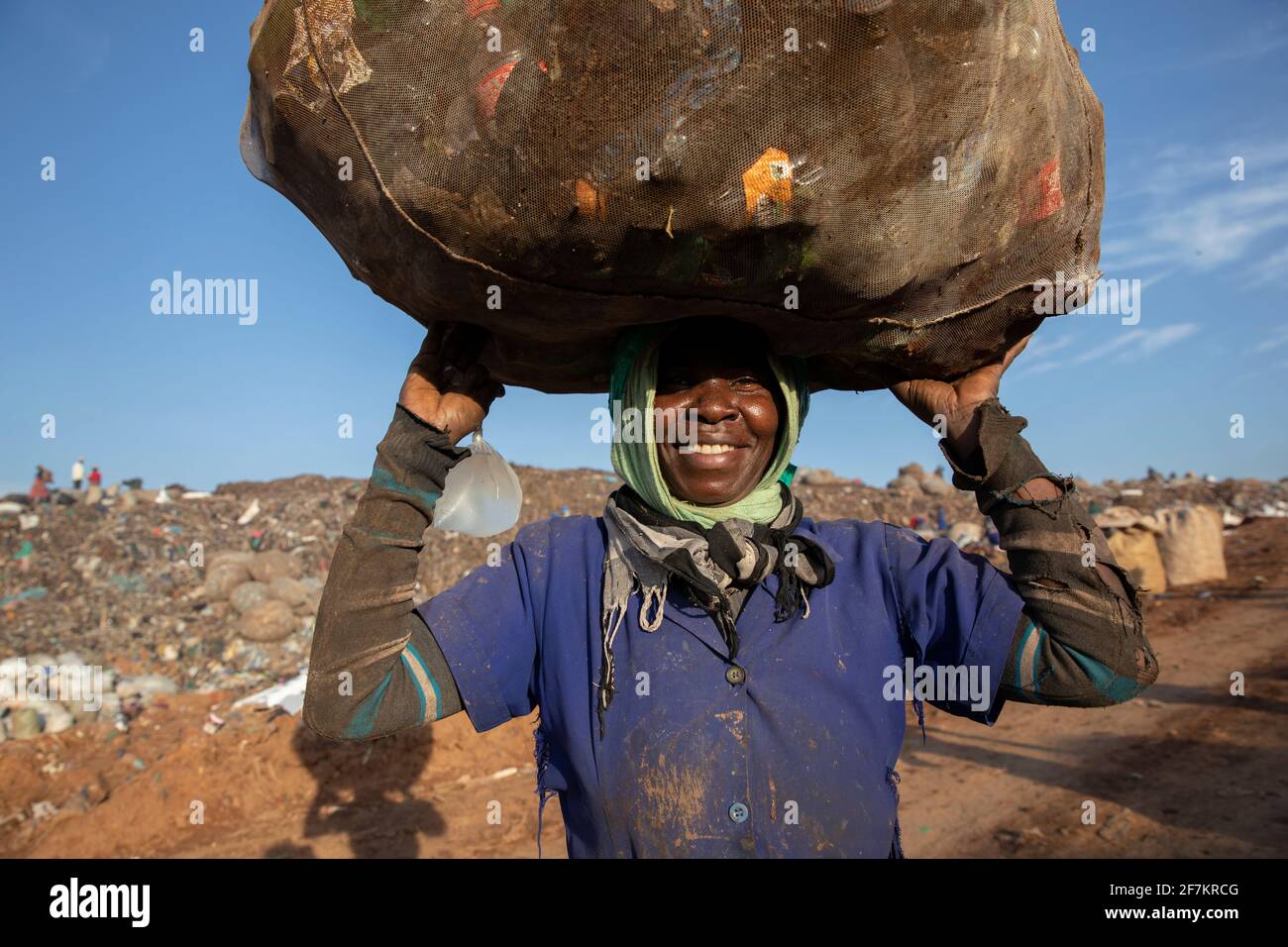 KAMPALA, UGANDA: A worker stands with a bag full of recycled material ...