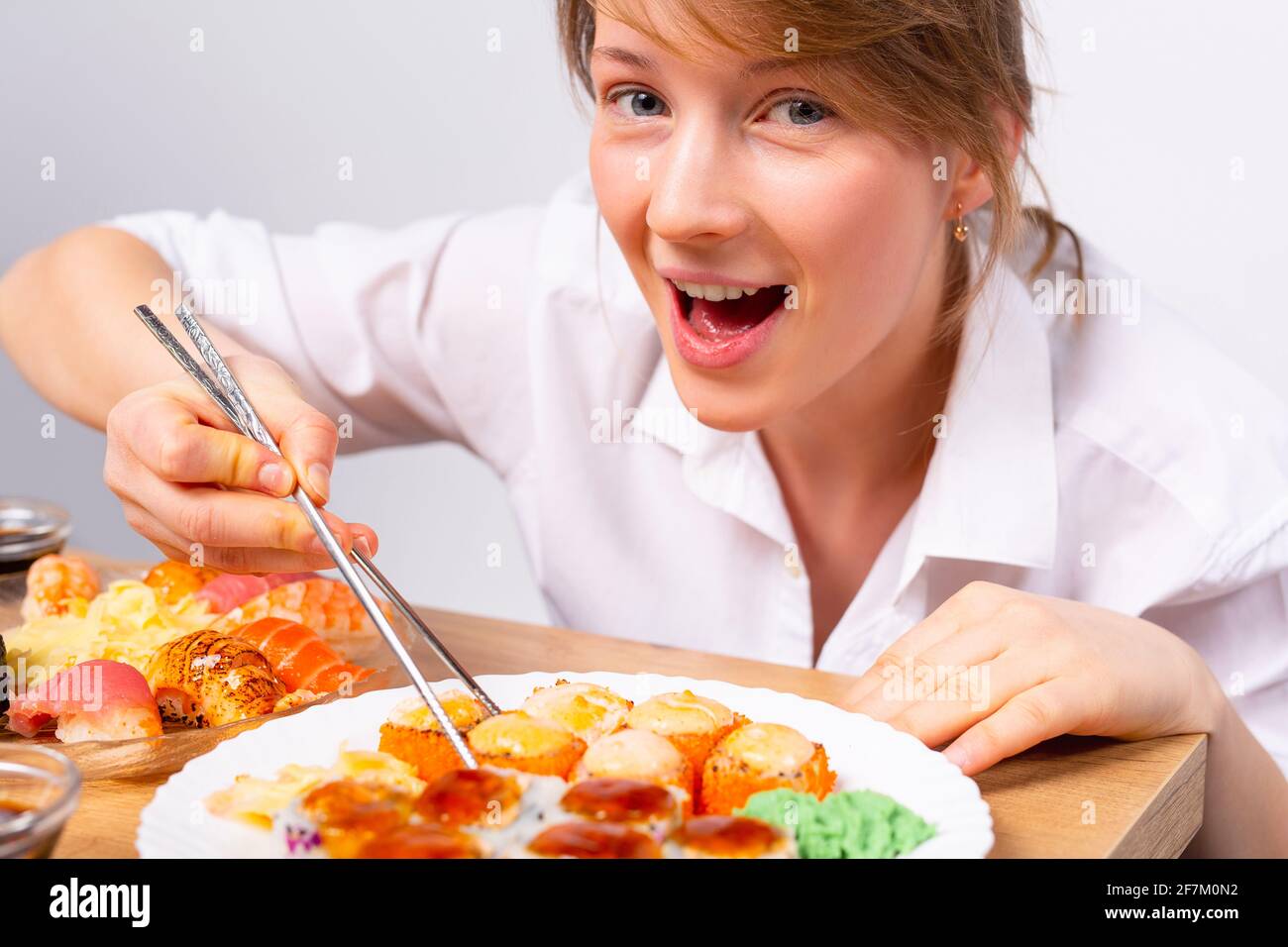 Hungry girl and Japanese food. The girl with appetite opened her mouth ...