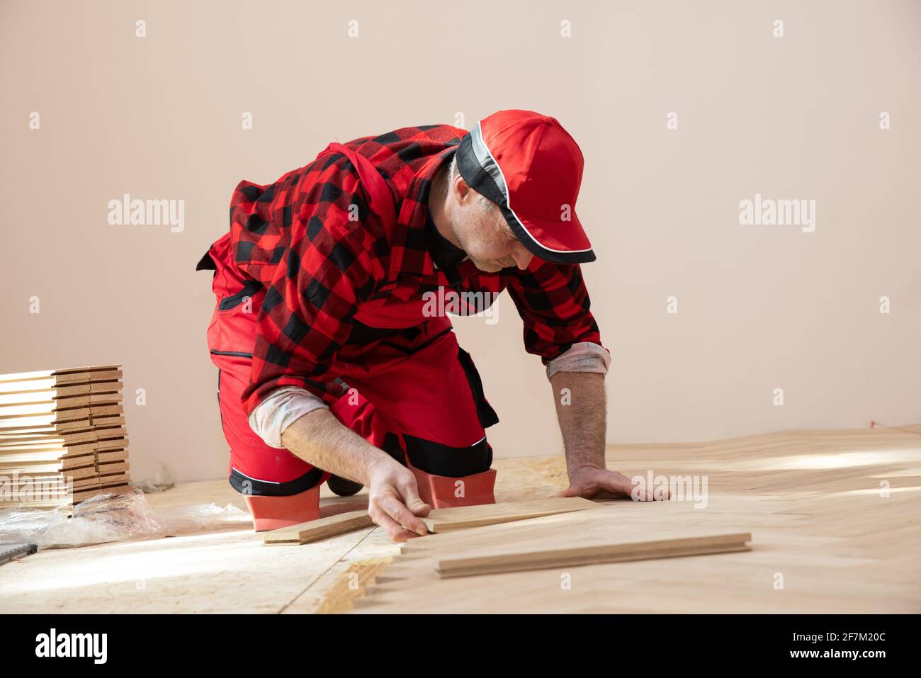 Handyman installing wooden flooring, Worker laying parquet flooring ...