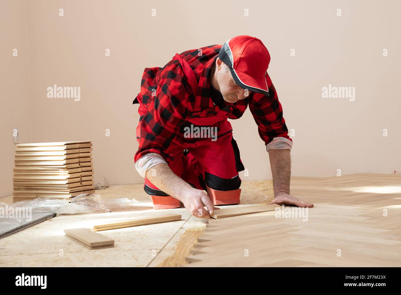 Worker installing parquet floor during home renovation, Construction in ...