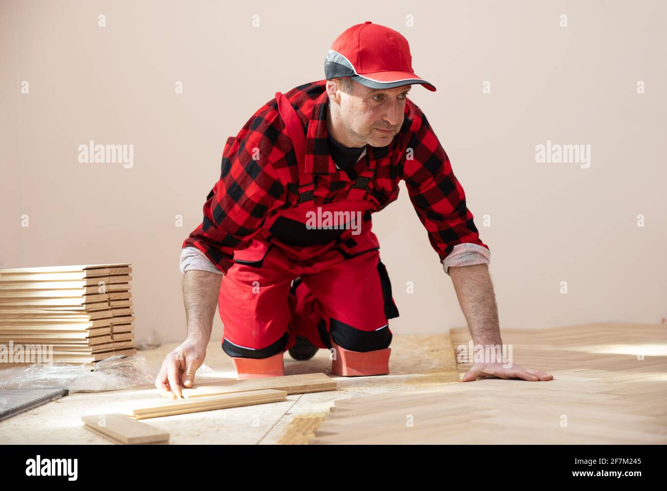 Man laying parquet flooring, worker joining parquet floor. The builder ...