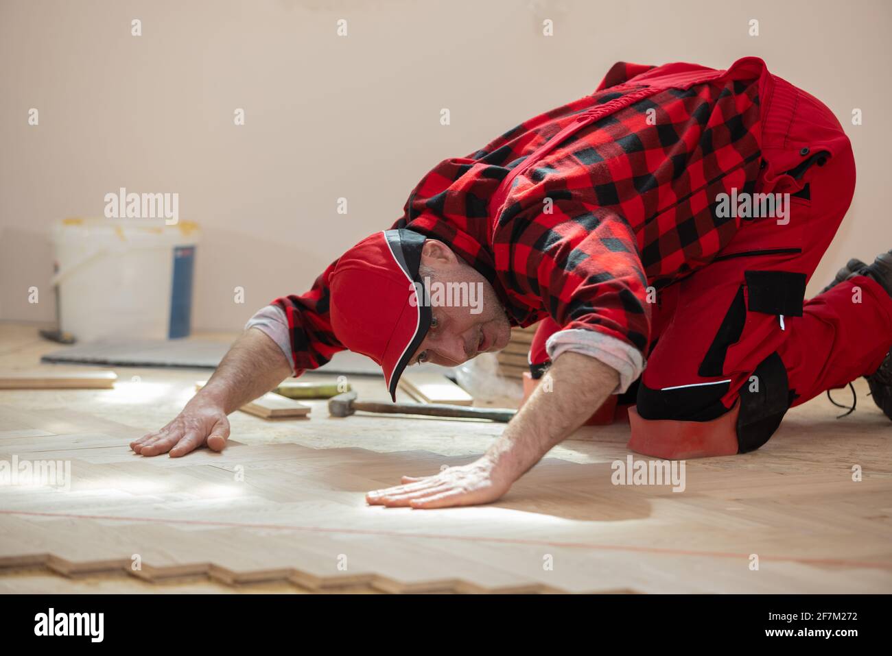 Man laying parquet flooring, worker joining parquet floor. The builder ...