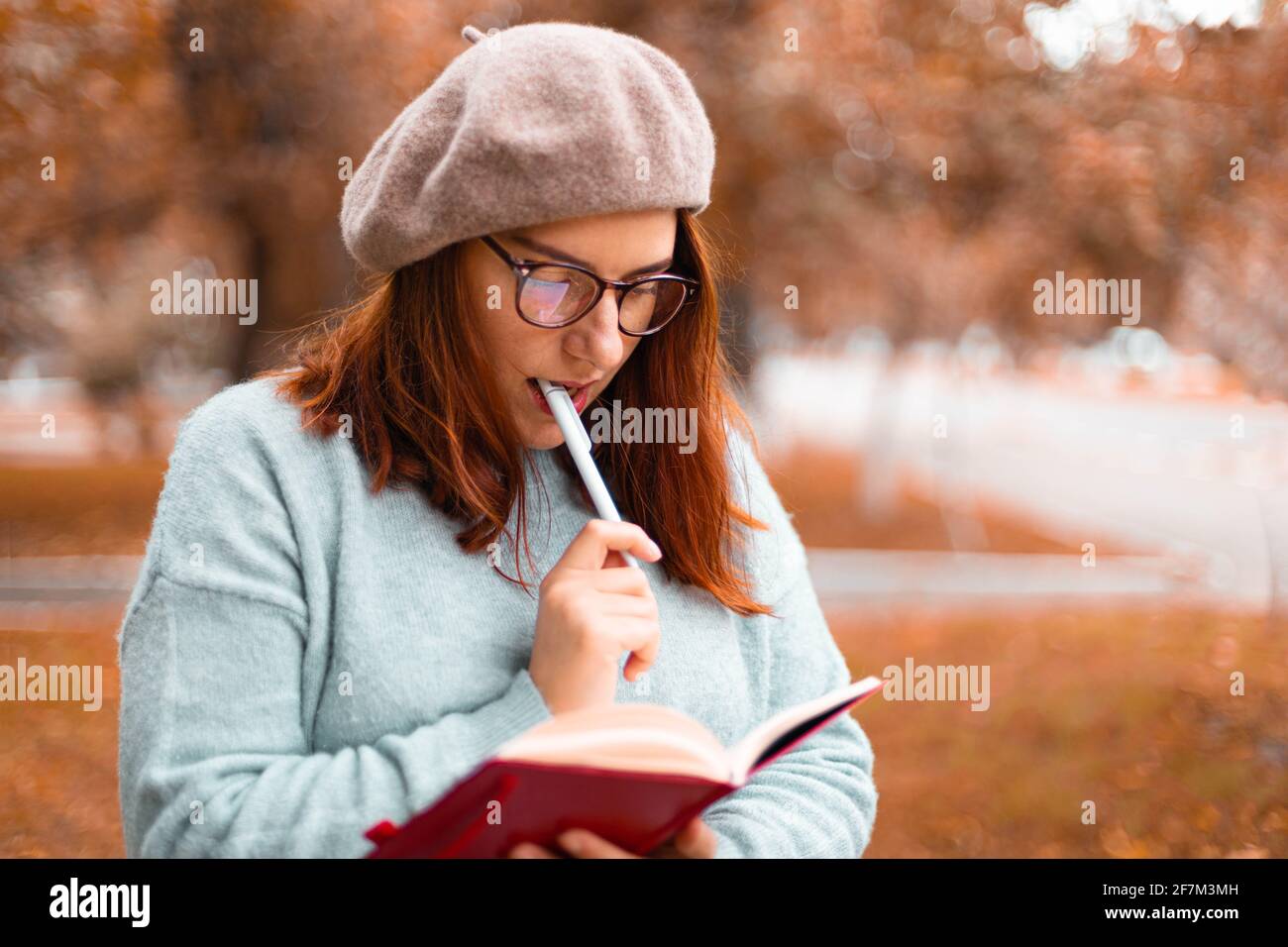 Cute student girl writing notes in notebook sitting outdoors in nature ...