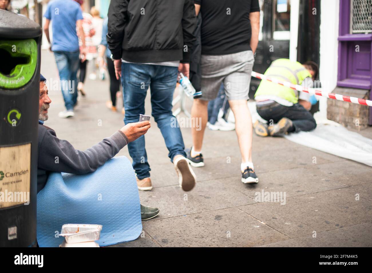 Elderly poor man begging on high street, while two careless boys ...