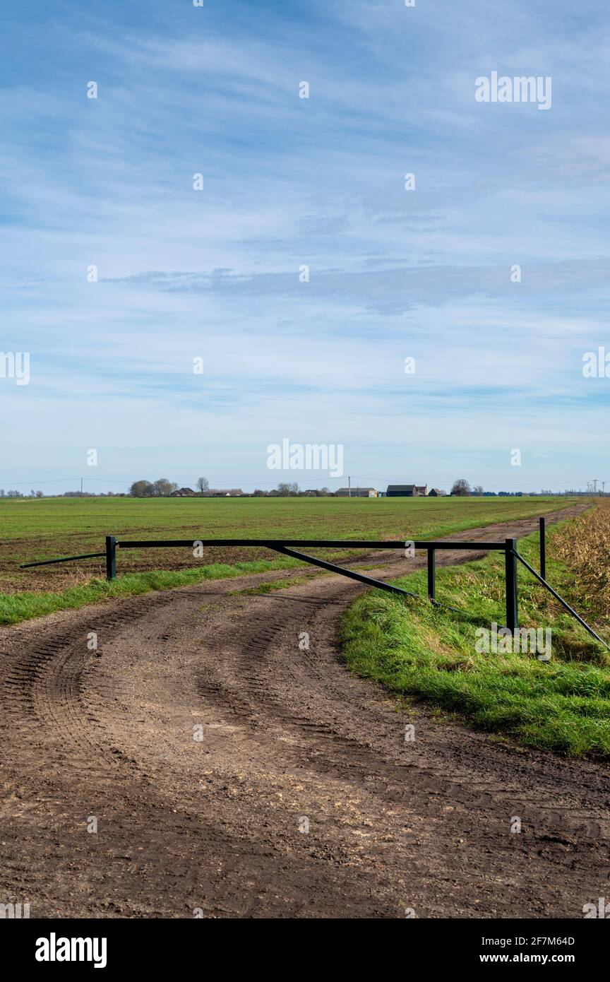 A metal gate or barrier across a remote and isolated farm track in flat ...