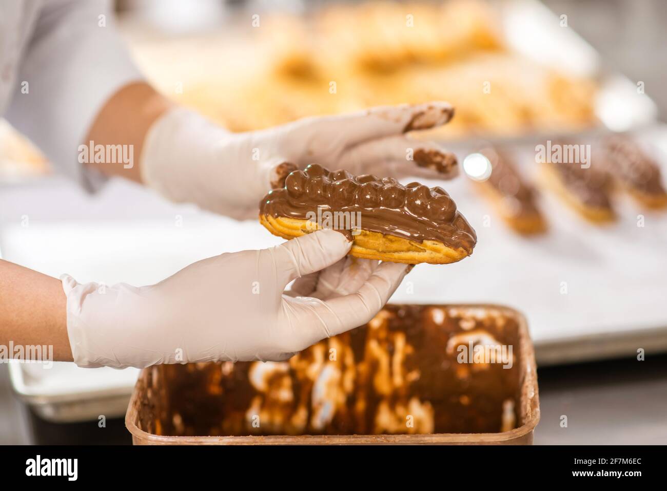 Pastry chefs hands holding eclair in chocolate topping Stock Photo - Alamy
