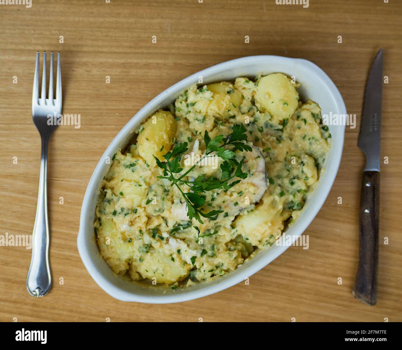 Hake on a green sauce with parsley leaves in a ceramic platter with ...