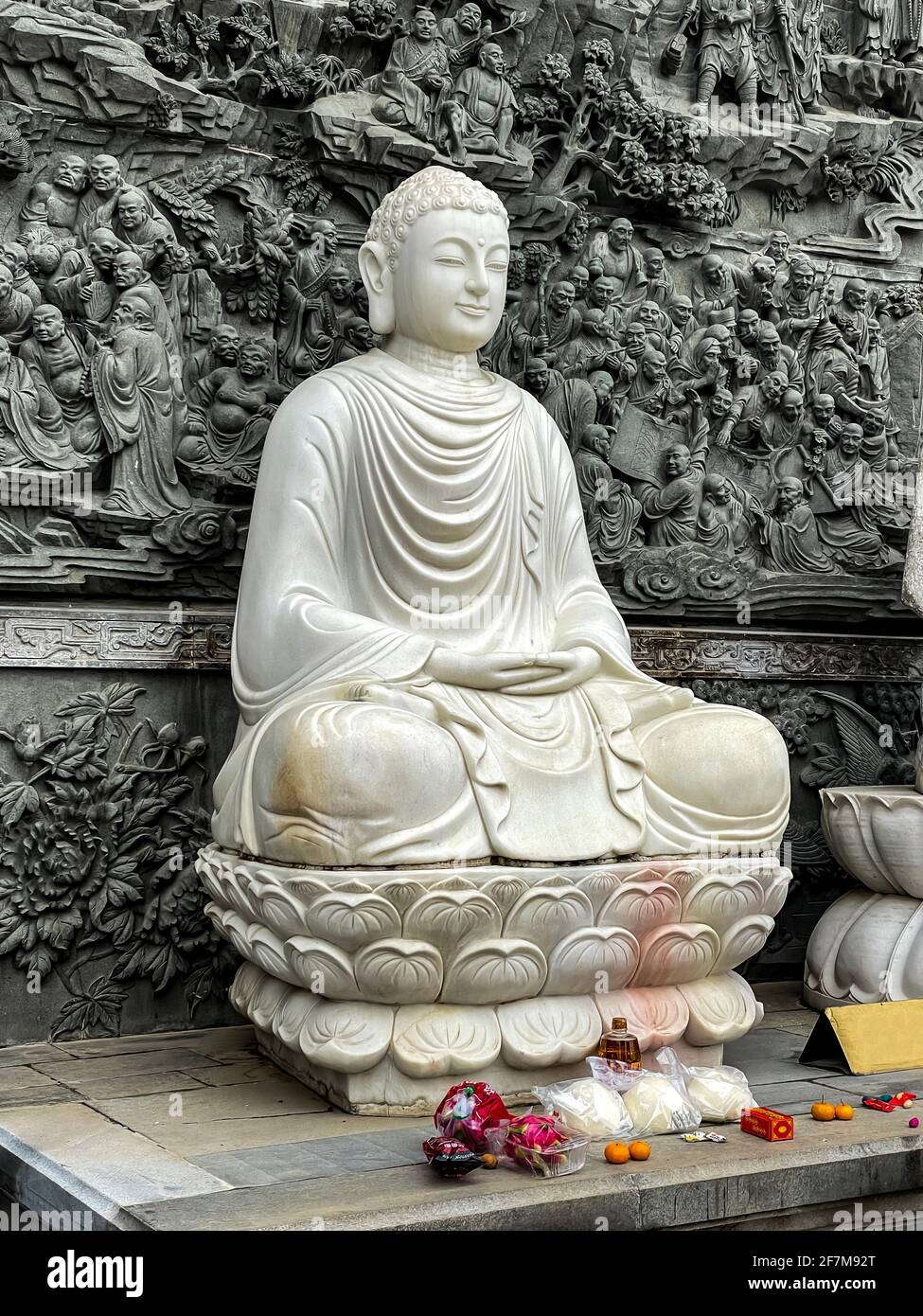 Detail of Buddha statue by carvings on a wall of Linguang monastery at ...