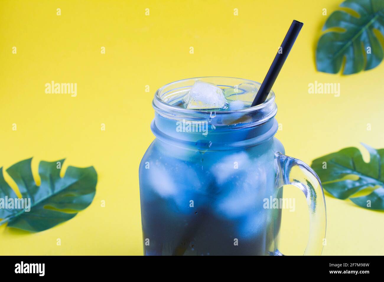 Iced blue cocktail in the glass on the tropical background. Copy space ...