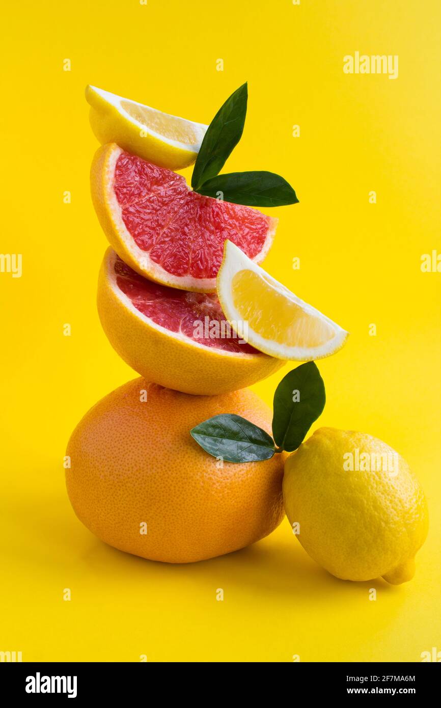 Pyramid of grapefruit and lemon in balance on the yellow background ...