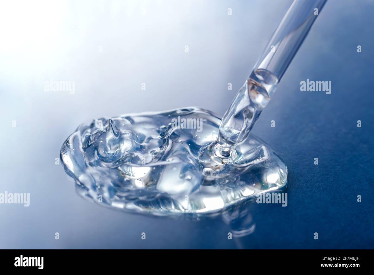 Liquid transparent gel serum swatch with pipette on blue color glass ...