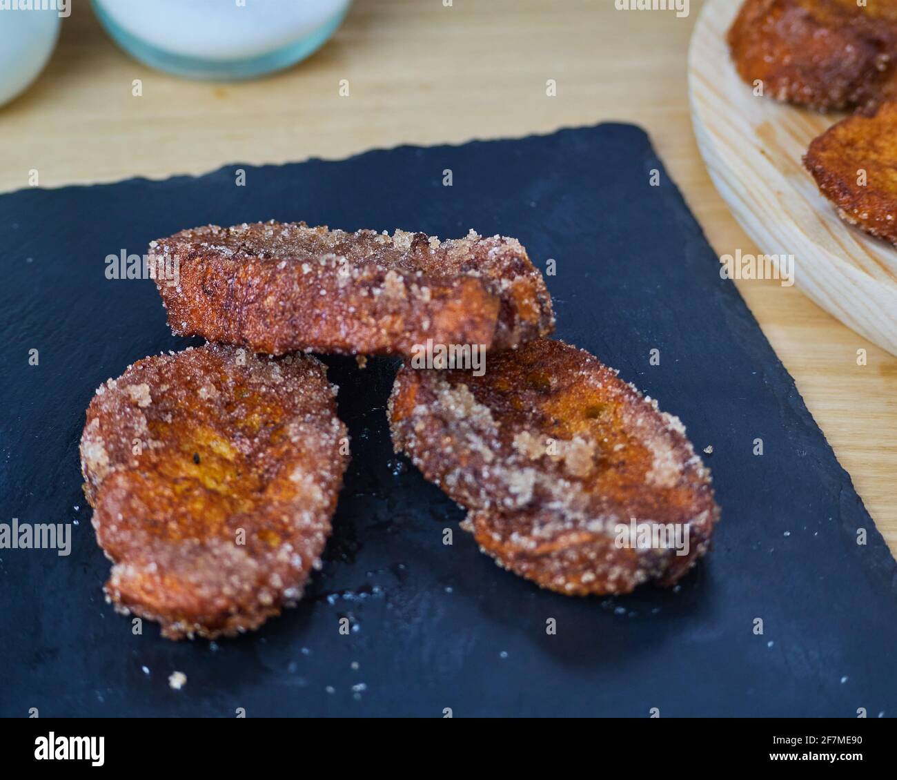 Traditional homemade Spanish Torrijas on a black slate board decorated ...