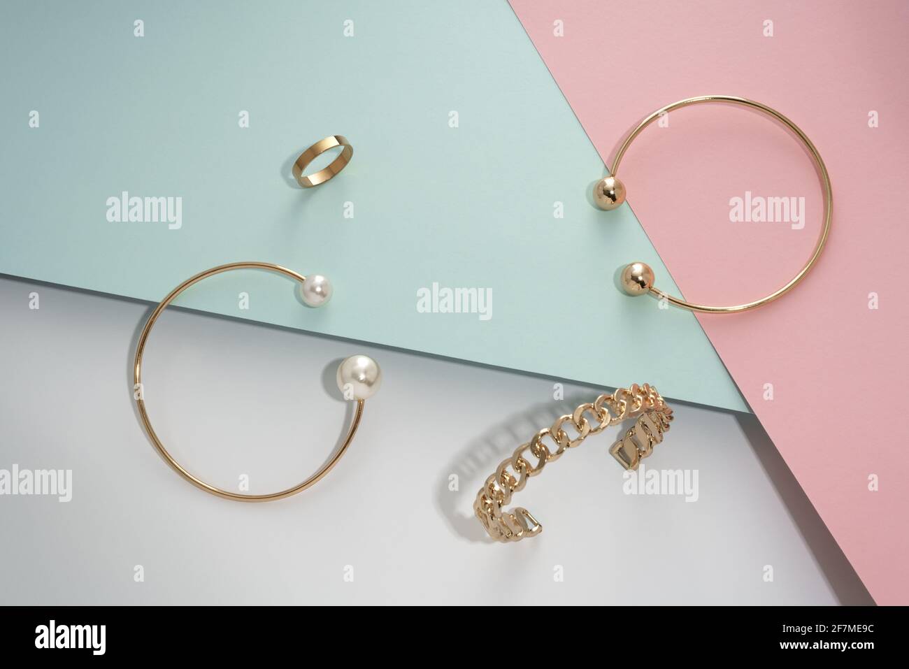 Golden bracelets set and ring on pastel colors background Stock Photo ...