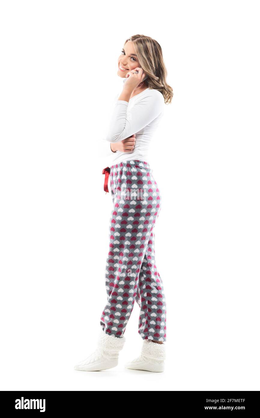 Side view of beautiful smiling young woman in pajamas talking on the ...