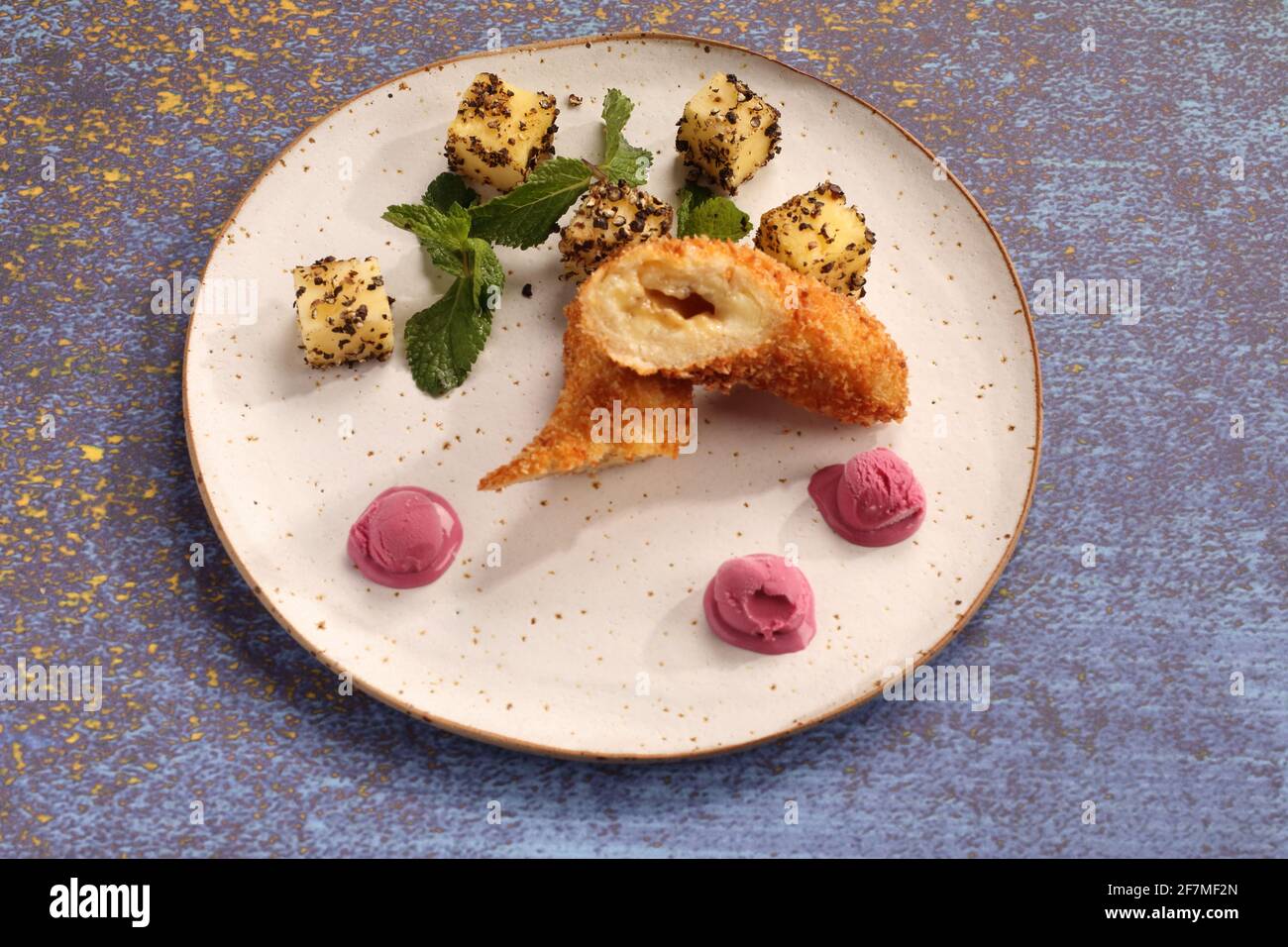 Banana Fritter with Pineapple chunks and a raspberry ice-cream arranged ...